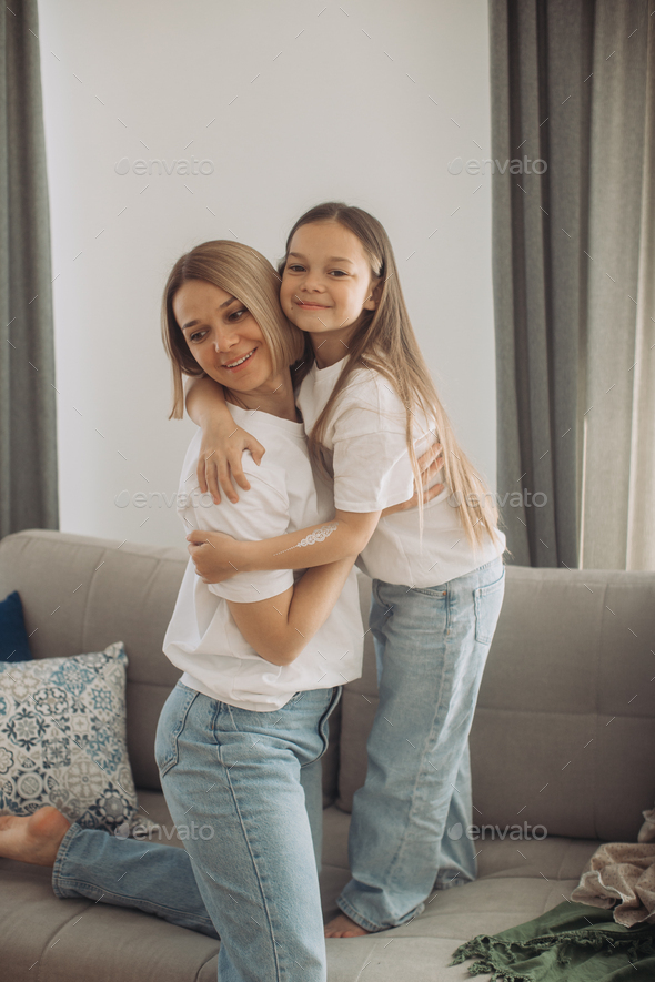 Cheerful mom playing laughing with little daughter on sofa. Stock Photo by dmytros9
